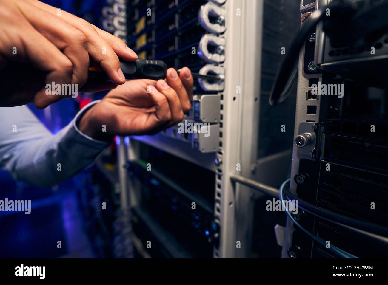 Technician attaching mounted hardware component to front of server rack ...
