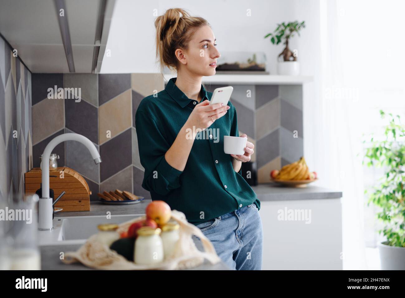 Portrait of young woman student with coffee at home, using smartphone ...