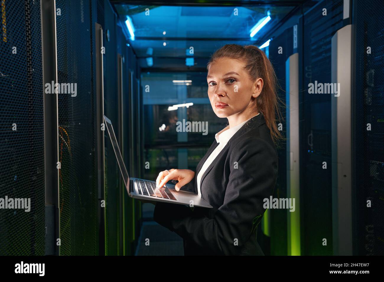 Determined woman with laptop working with servers in data center Stock ...
