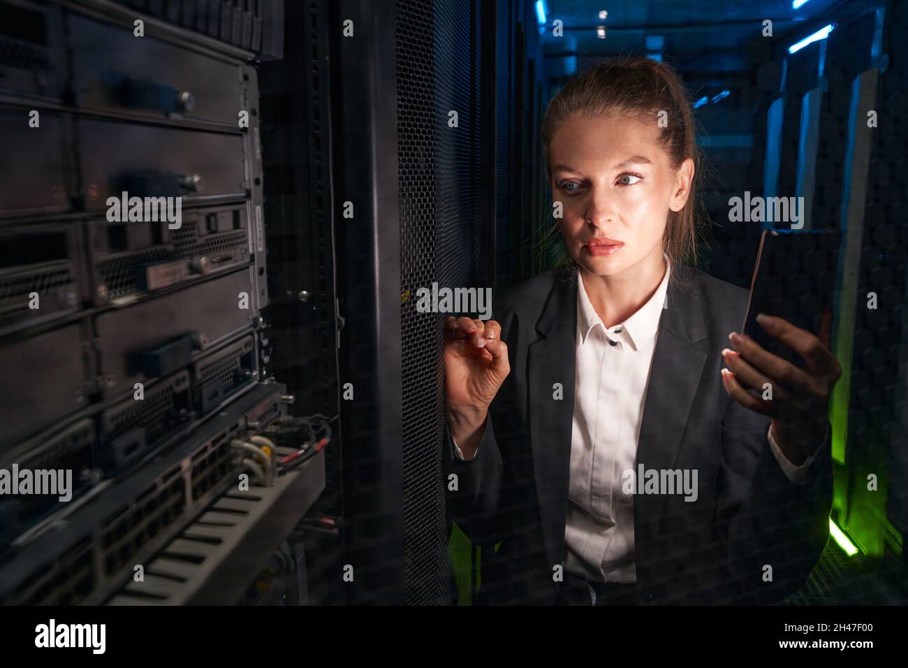 Pretty female administrator checking network connections in server room ...