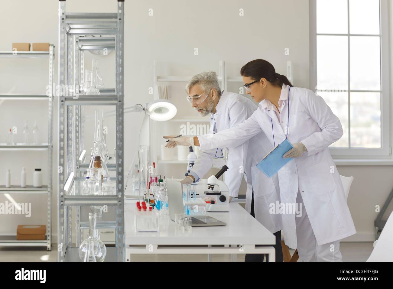 Senior male lab supervisor young female assistant check analysis result ...