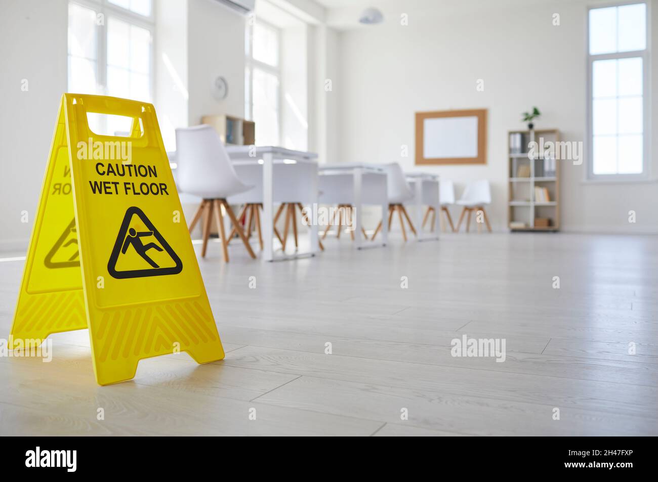 Yellow sign that reads Caution Wet Floor standing in clean empty school ...