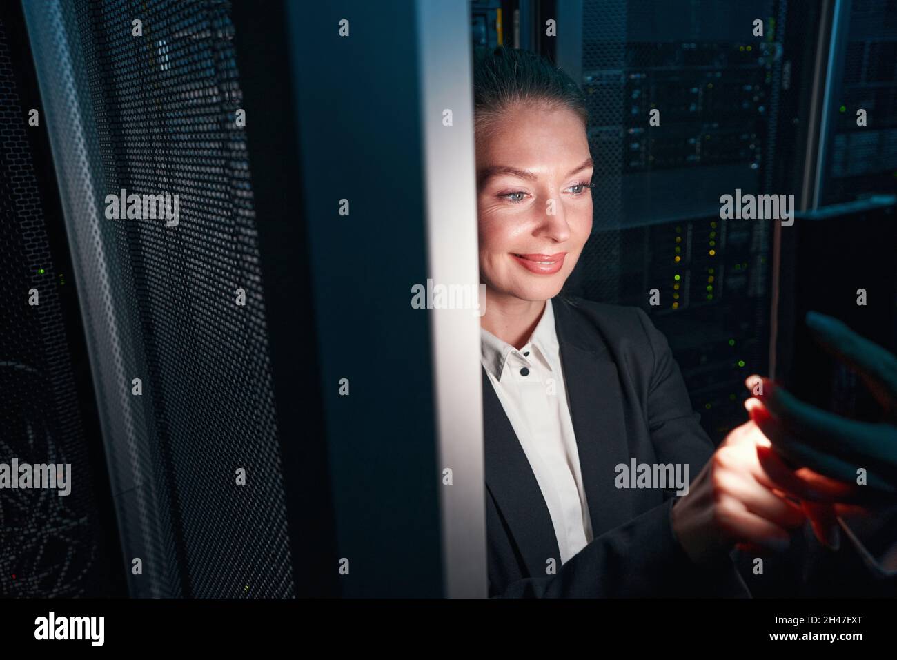 Cheerful woman network engineer working in server room Stock Photo - Alamy