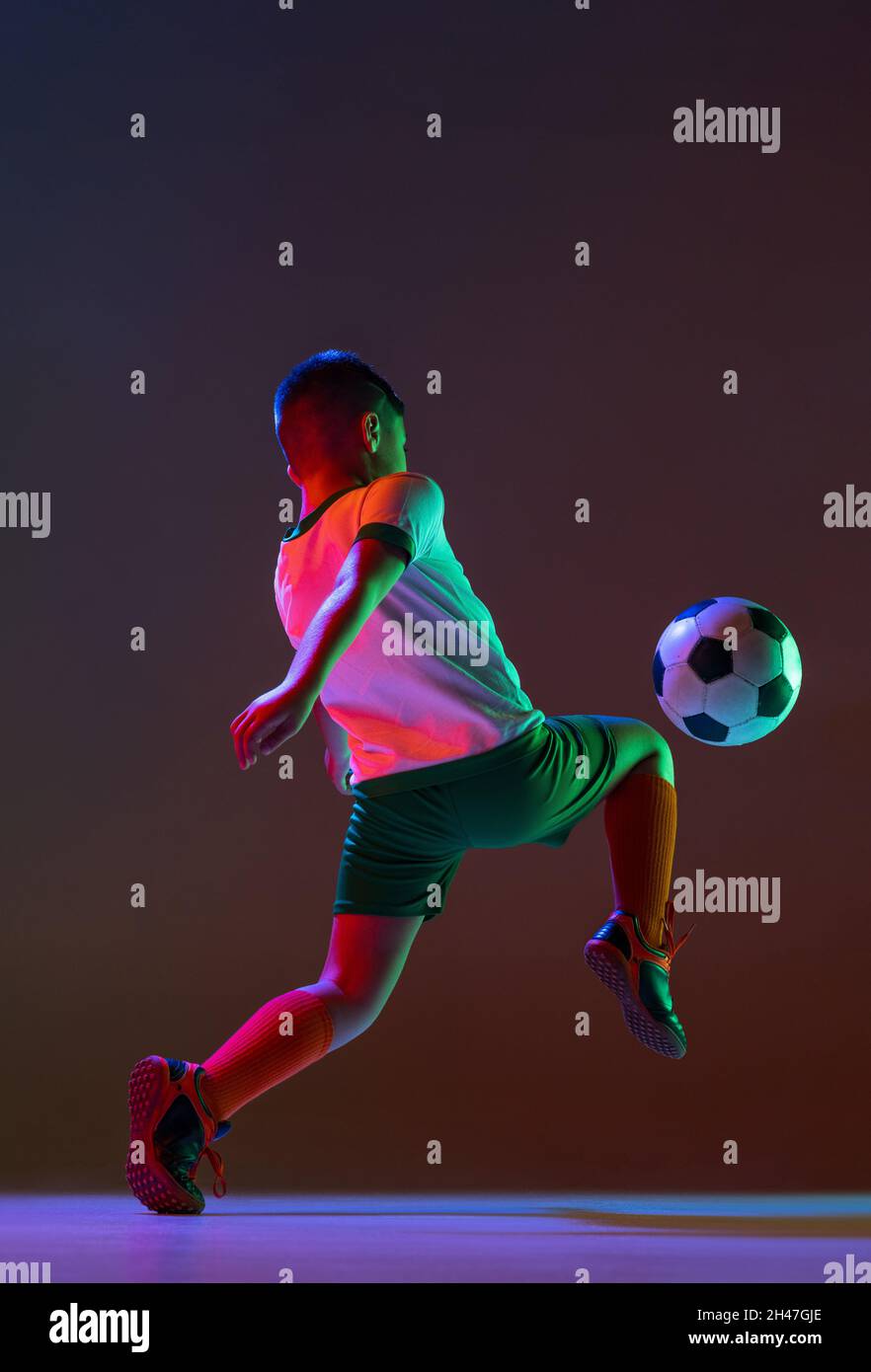 Full-length portrait of boy, child in motion training football isolated ...