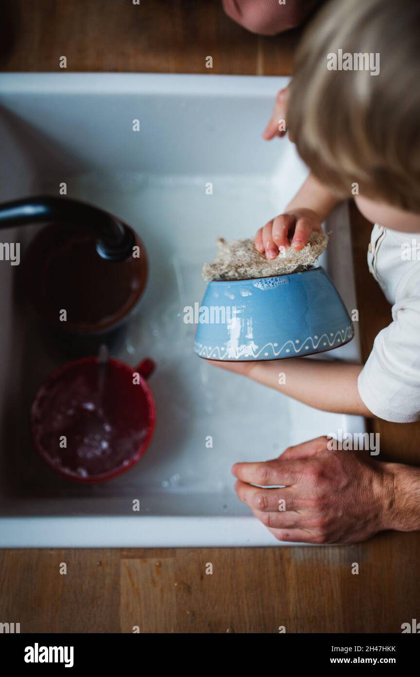 Top view of small boy with father washing dishes indoors at home, daily ...