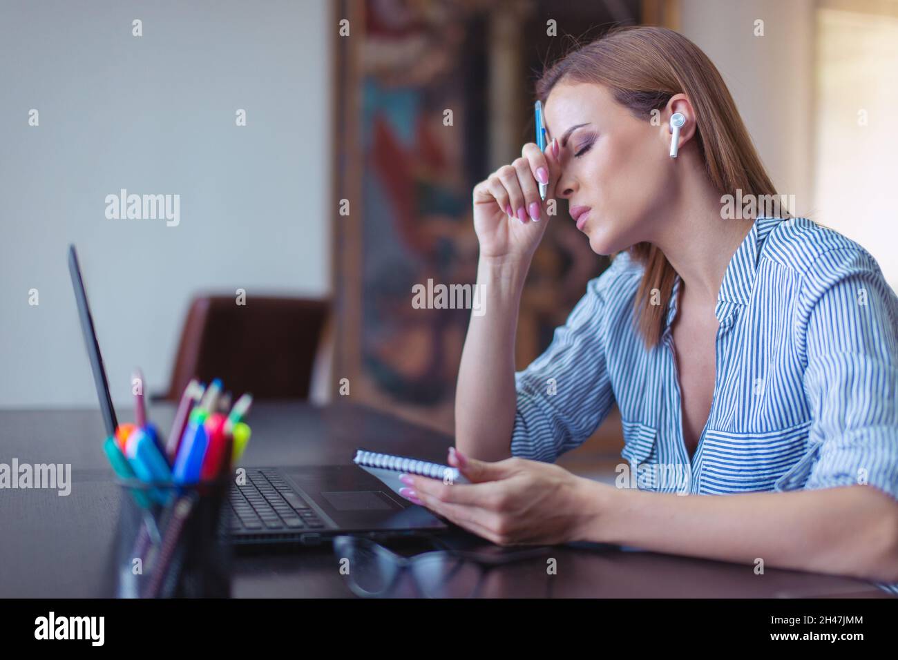 Tired university student with hands free device and notebook at laptop ...