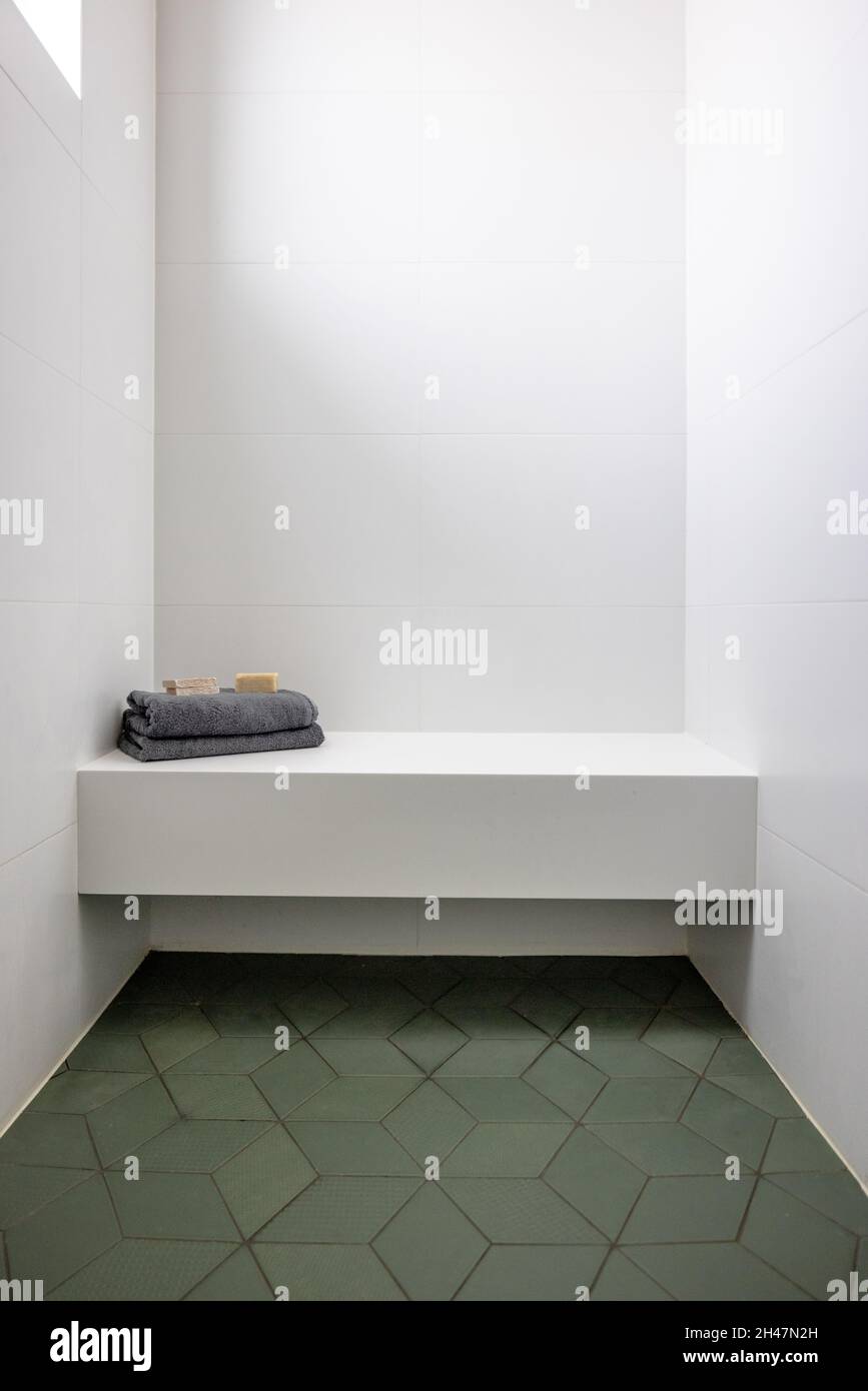 Shower with a green tile floor in the shape of a rhombus and a bench ...