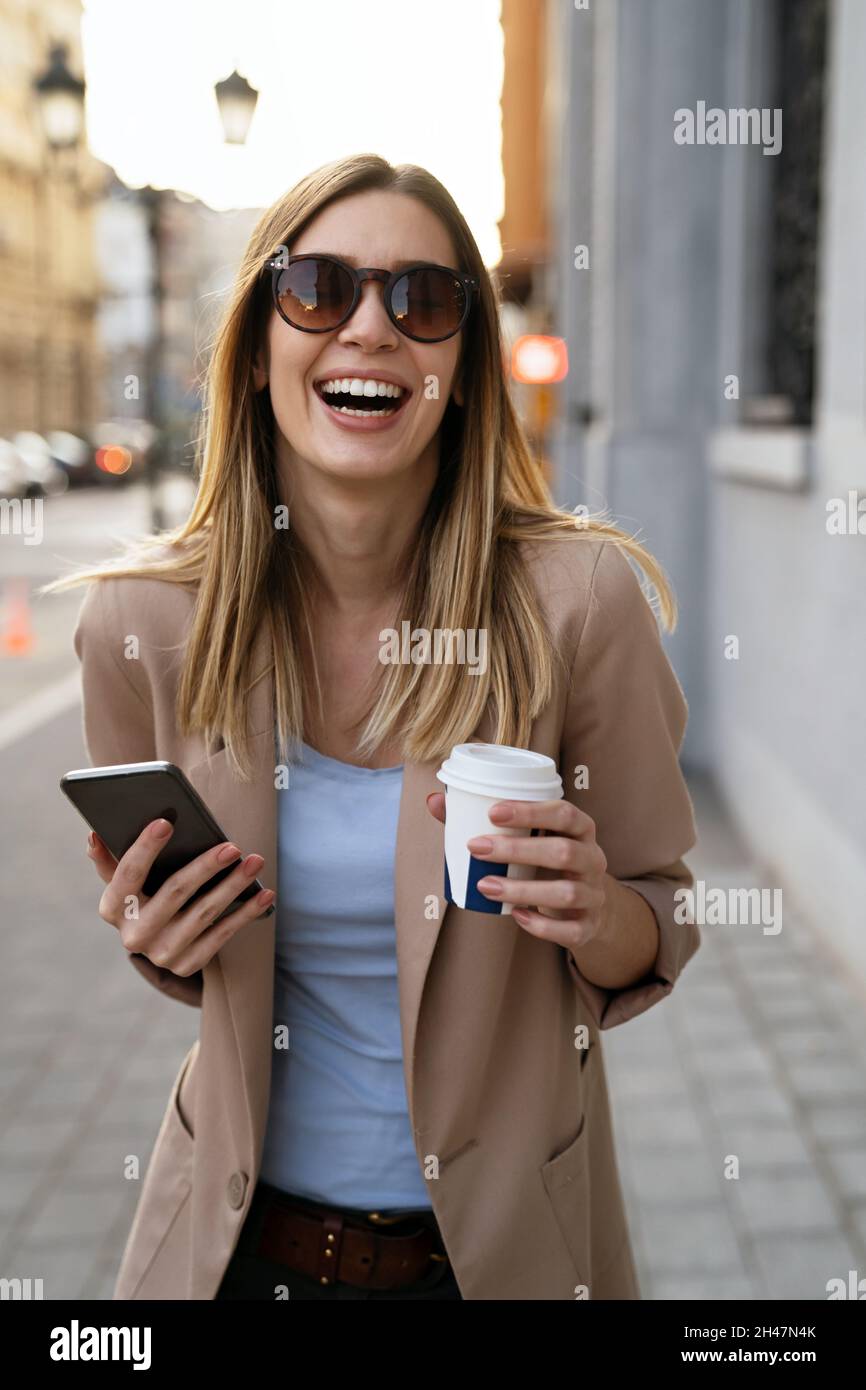 Beautiful young success woman with coffee using mobile phone against ...