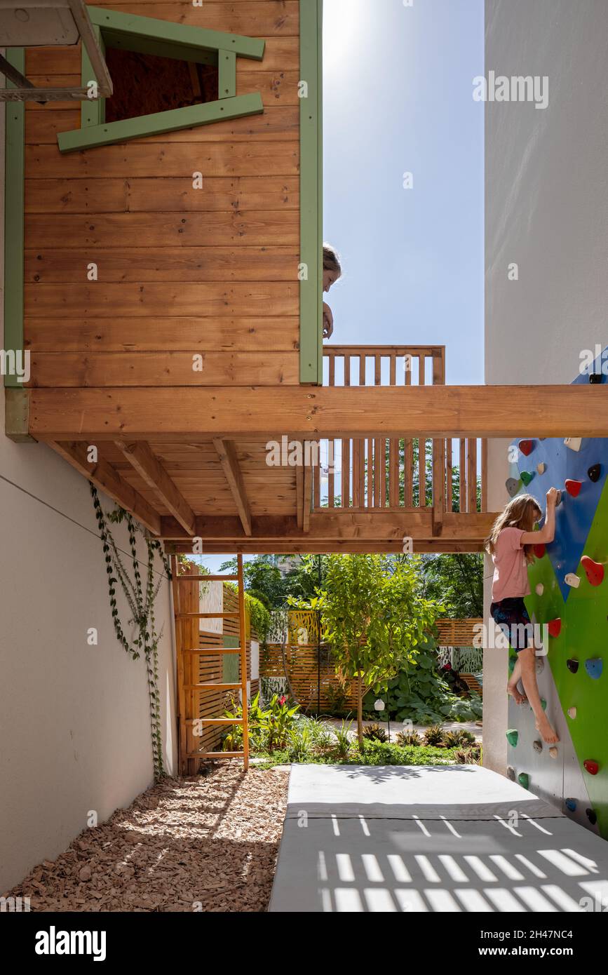 A climbing wall for children next to a wooden house in the back garden ...