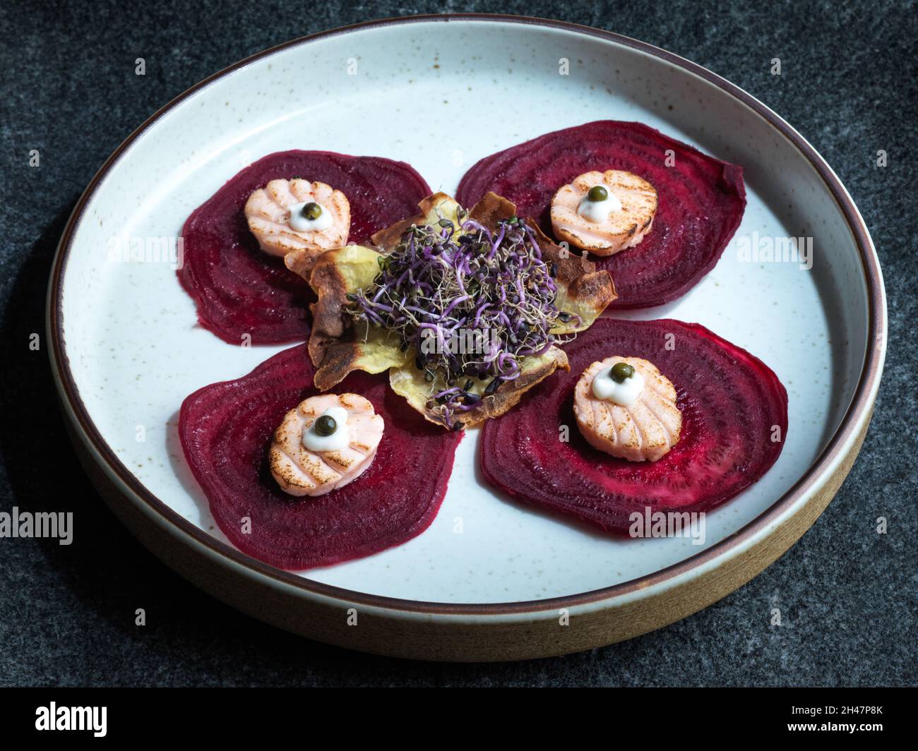 Torch seared salmon bites on thin beet root cuts with potato chips and ...