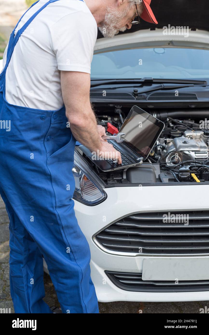 Car mechanic using laptop for checking car engine Stock Photo - Alamy