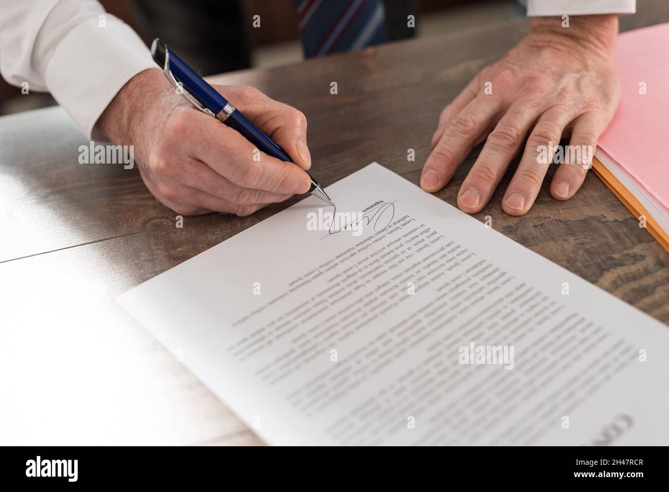 Businessman signing a document in office Stock Photo - Alamy