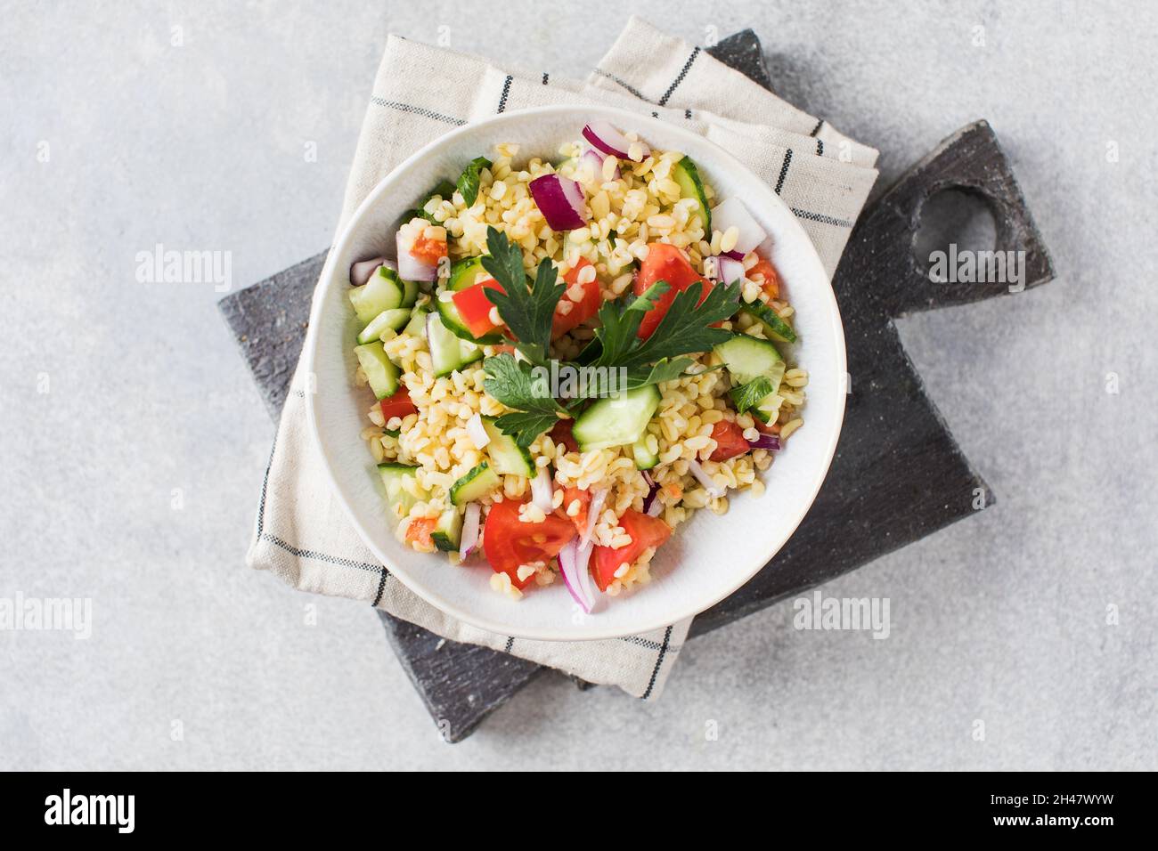 Vegetable and bulgur salad in deep bowl on white table decorated with ...