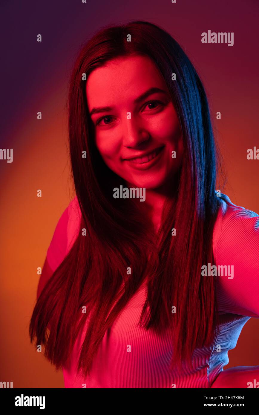 Charming happy girl isolated on dark studio background in neon light ...