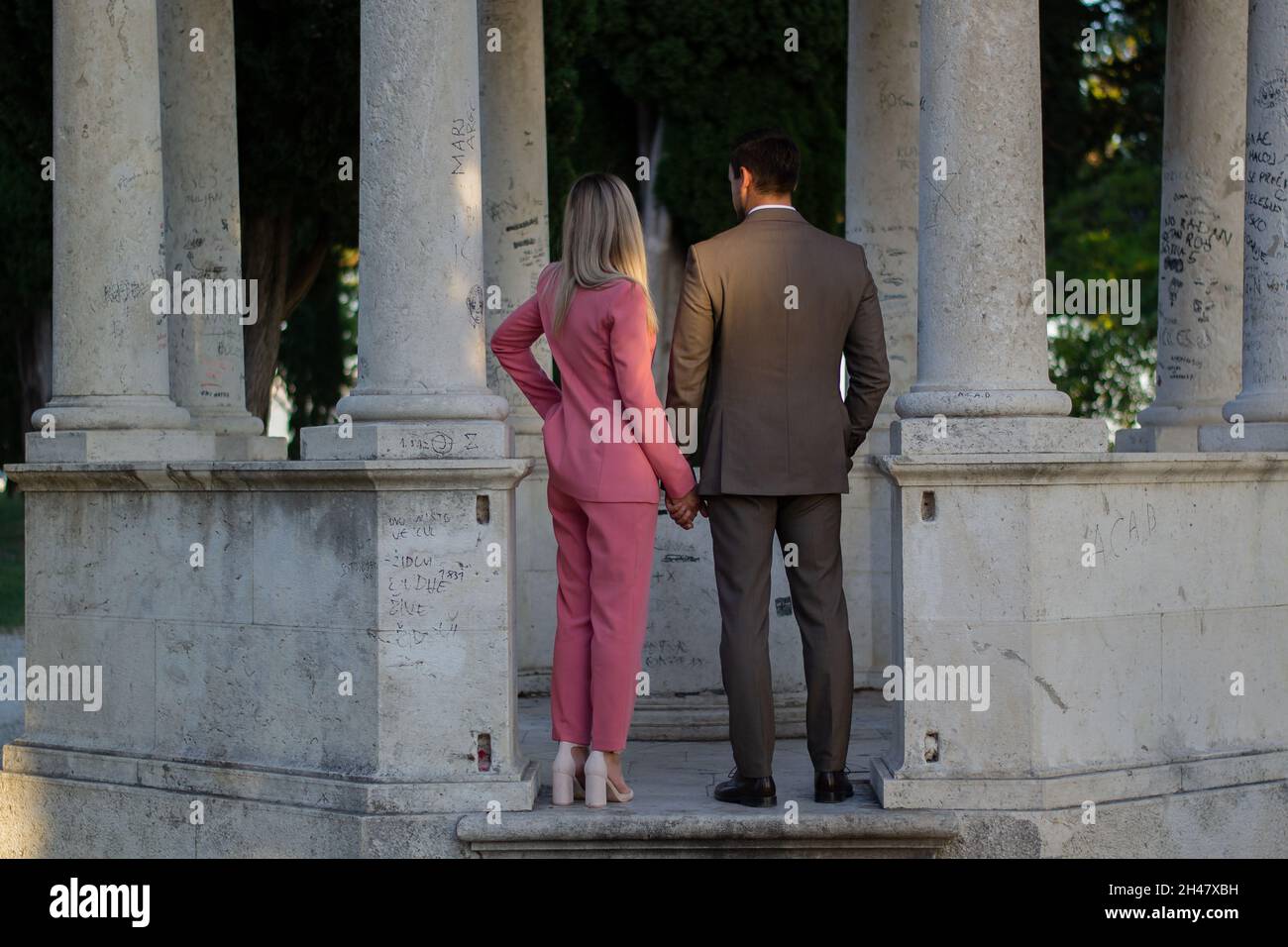 Lovely couple dressed in pink and brown suits holding hands, surrounded ...