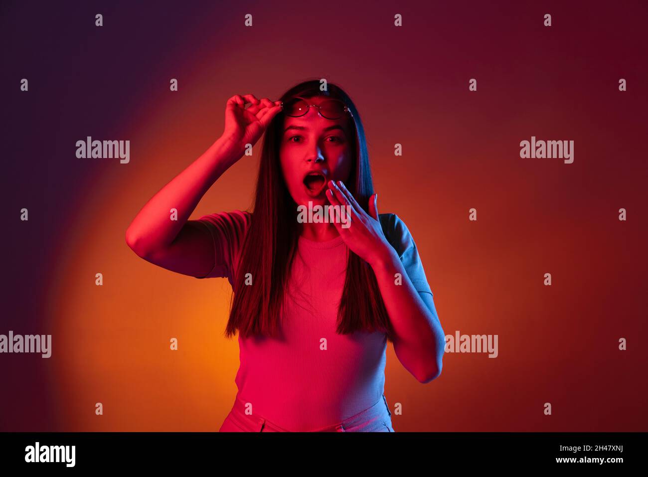Surprised, shocked girl isolated on dark studio background in neon ...