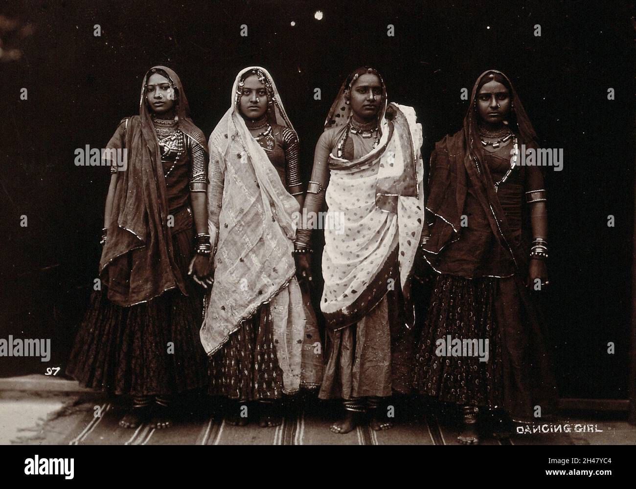 A troupe of nautch dancing girls, standing in a line holding hands, in ...