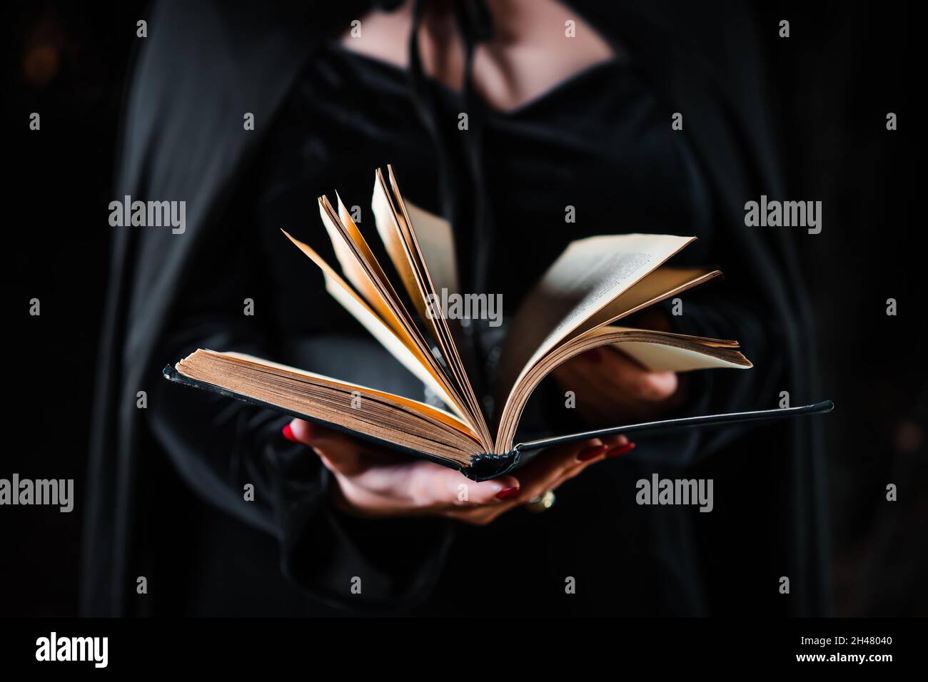 Witch in black costume reading black magic book. Halloween, spooky ...