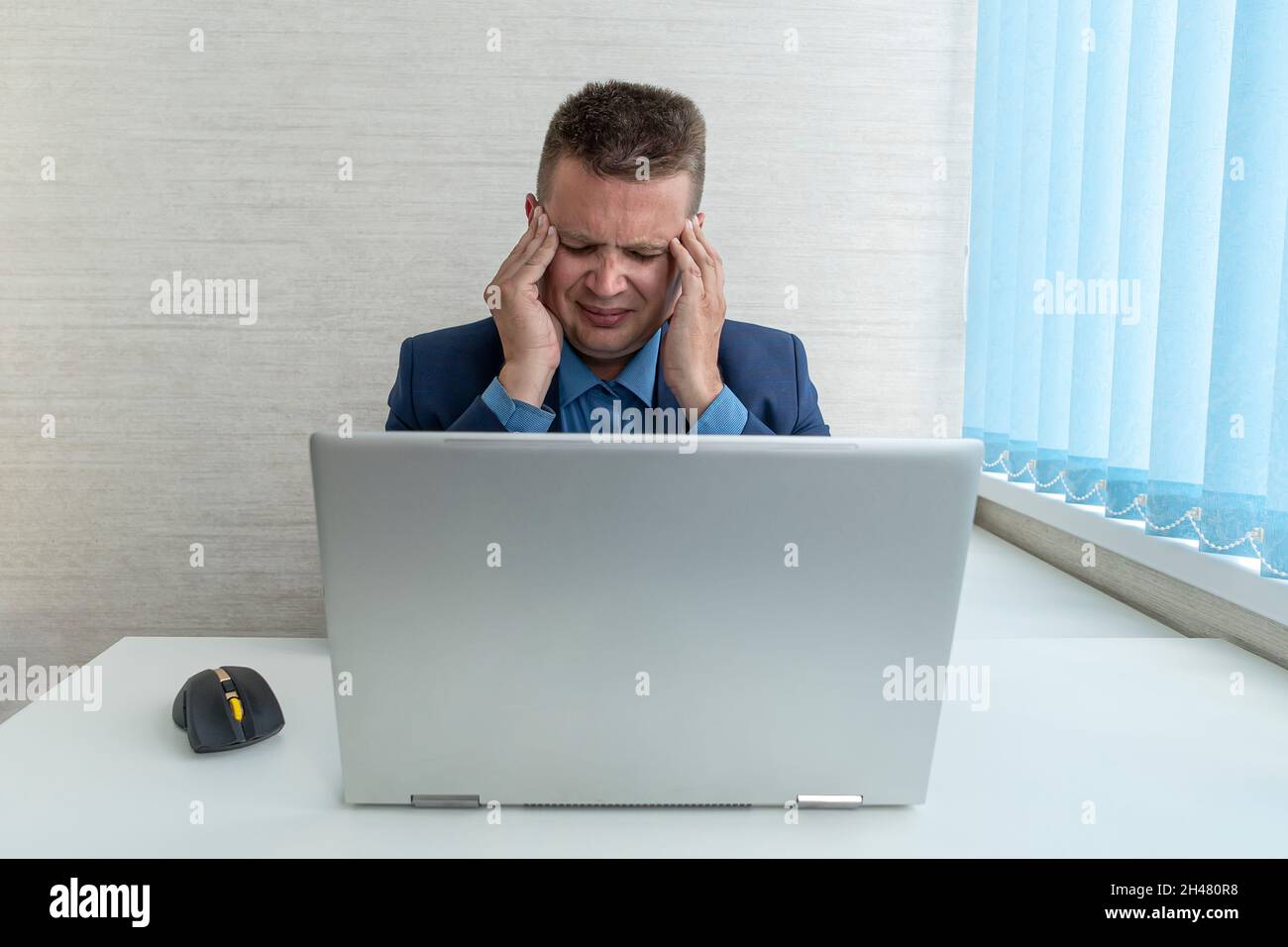 A man in a blue suit with a sore head in the office. The concept of ...
