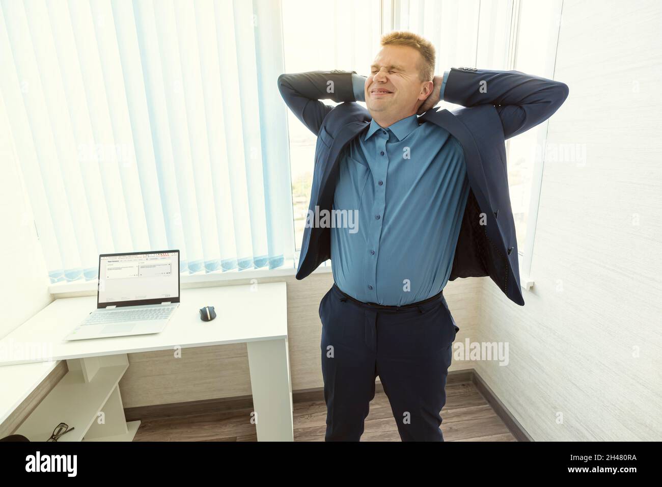Businessman stretching out at desk with laptop. Manager make deep ...