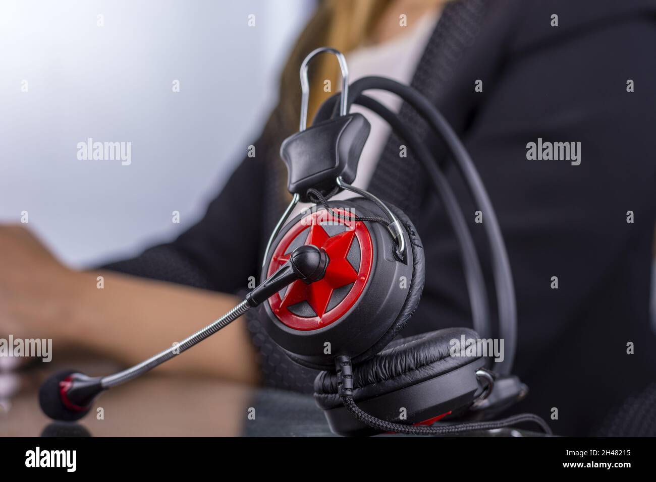 Desk with headset and female agent behind it Stock Photo - Alamy