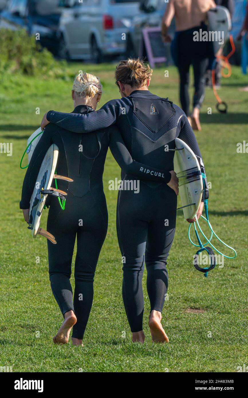 A male and female surfer with their arms around each other and carrying ...