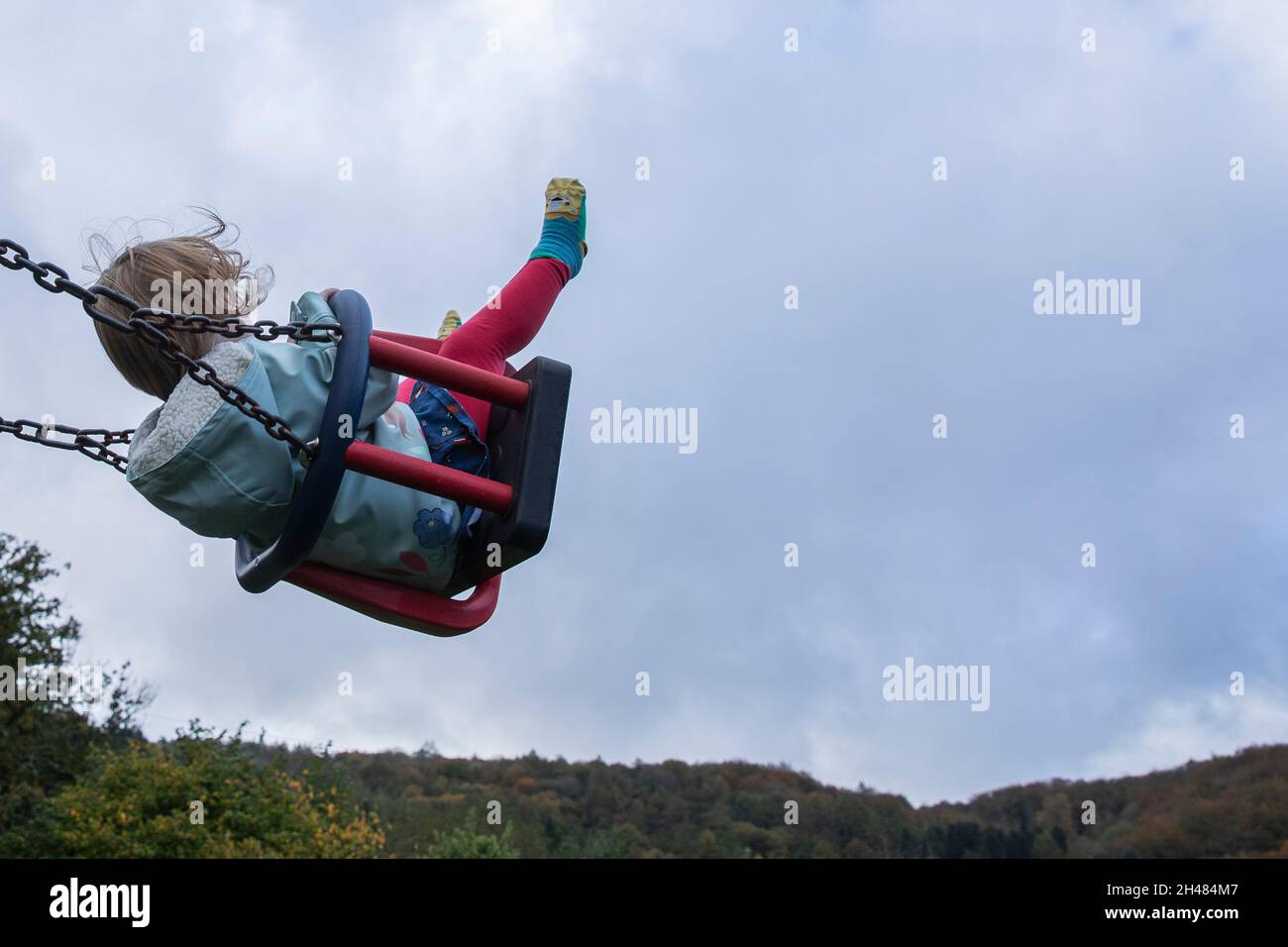 The back of a child swinging high in the air in a playground baby-swing Stock Photo - Alamy