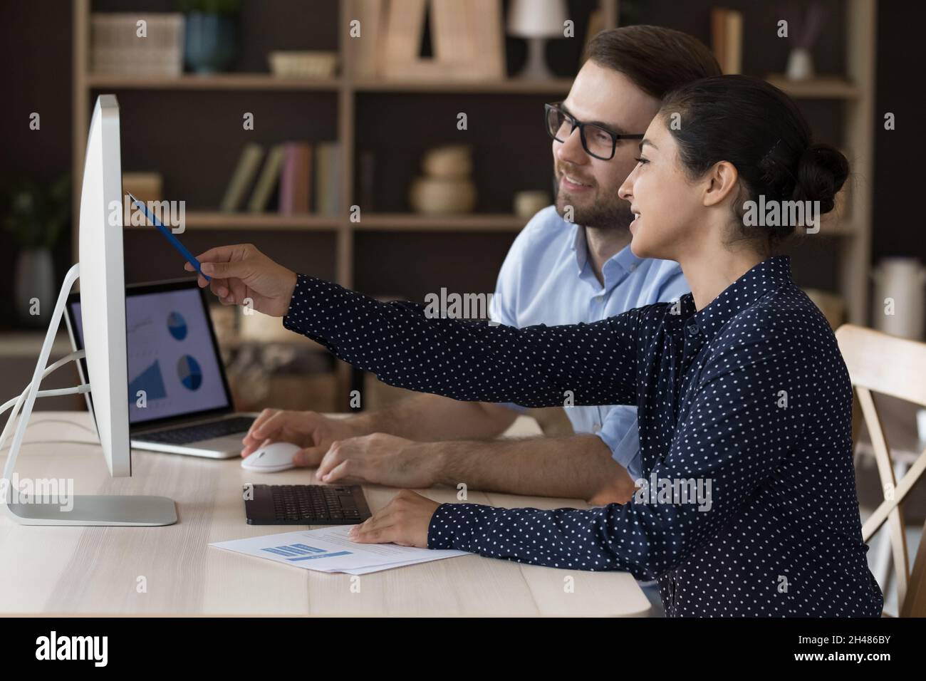 Happy young Indian employee working on online project with colleague ...