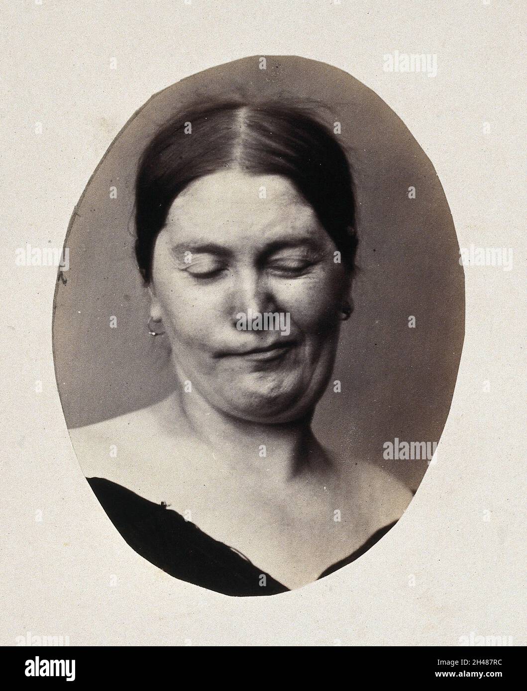 A woman's head and neck; her eyes are closed and her mouth twisted into ...