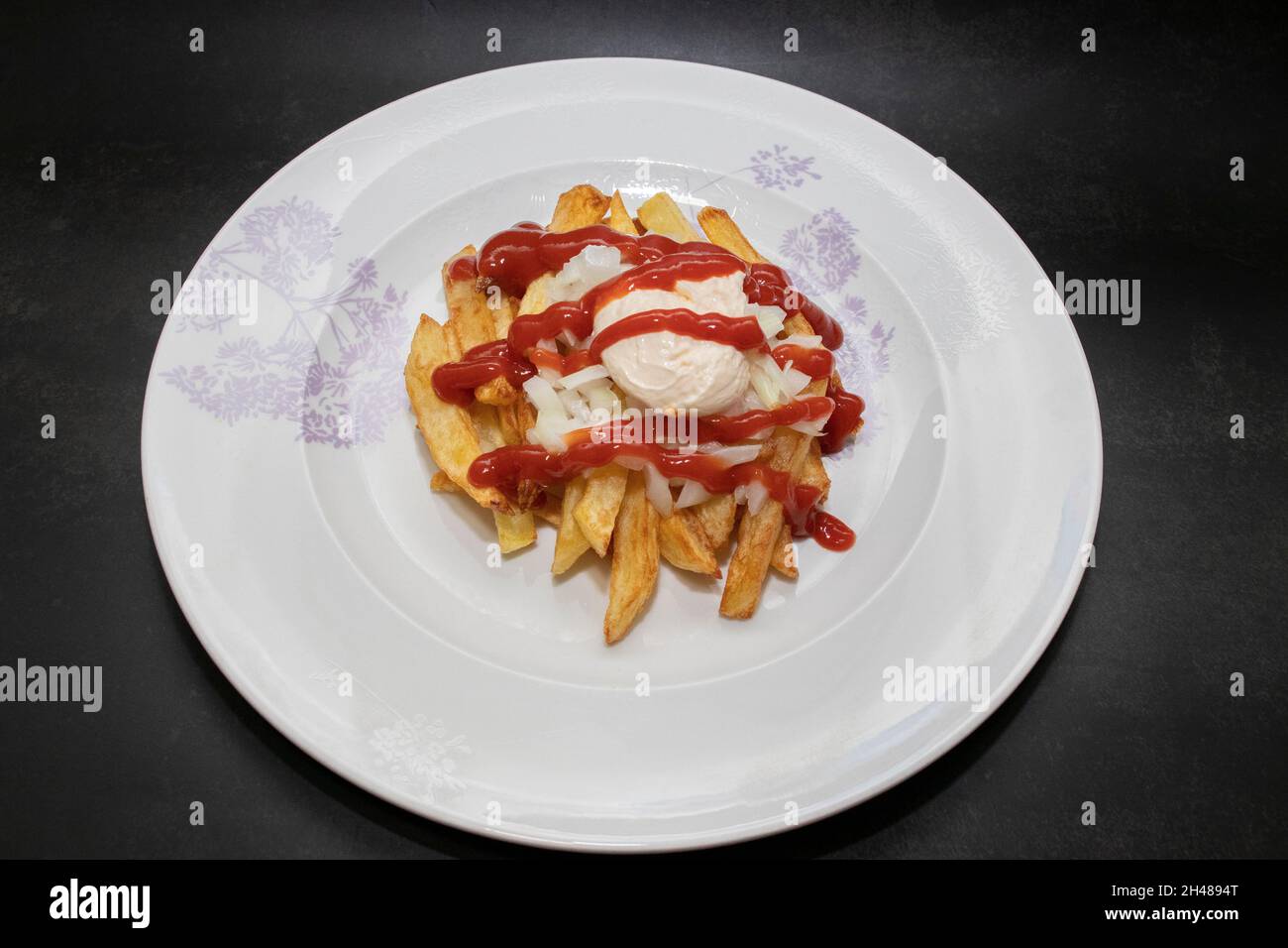 Frites spezial with mayonnaise, ketchup and onions,on a white plate ...