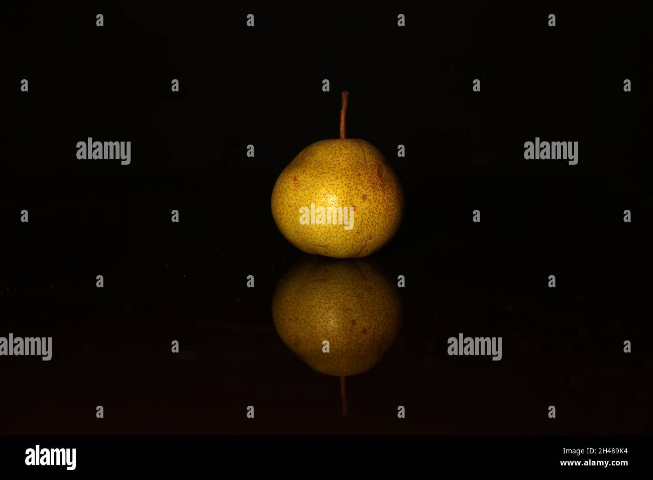 A yellow pear on a black background Stock Photo - Alamy