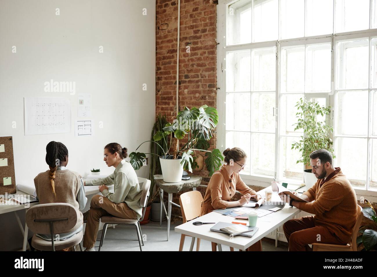 Wide angle portrait of diverse creative team working in modern studio ...