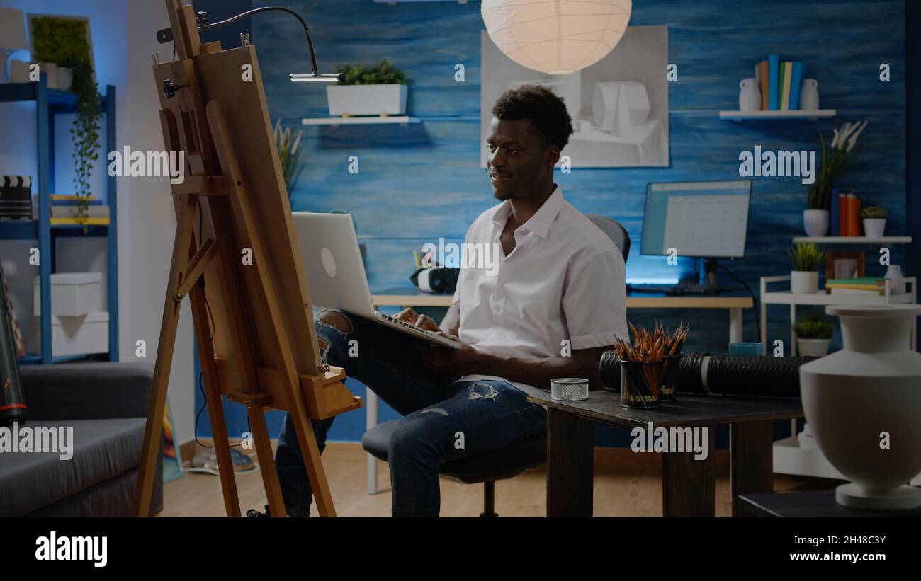 Black creative artist with laptop using technology for art design and ...