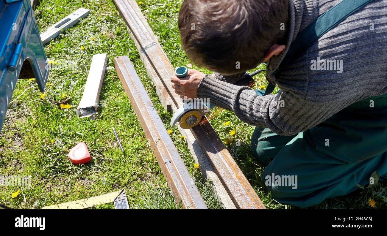 Man grinds a metal product with angle grinder outdoors. Metal ...