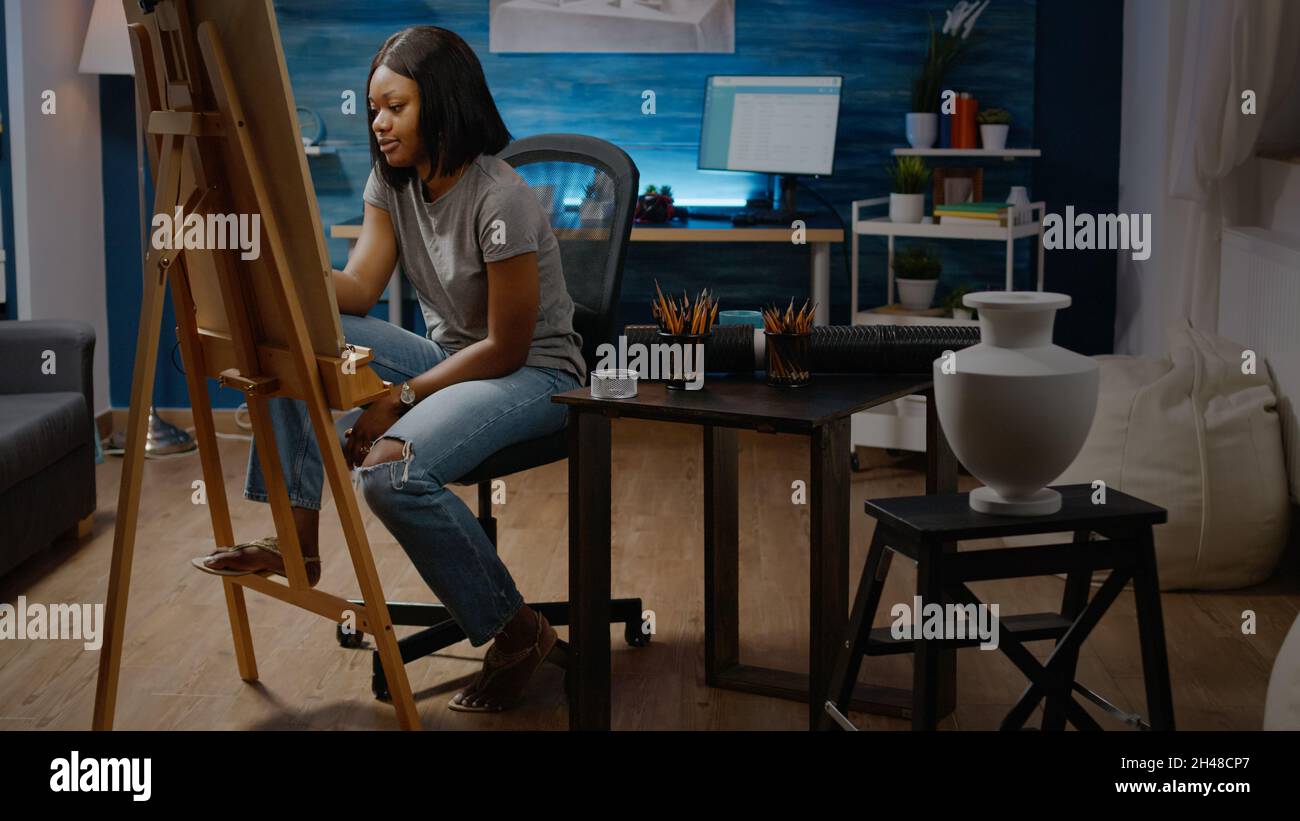 Black artistic person designing masterpiece of vase on table in artwork ...