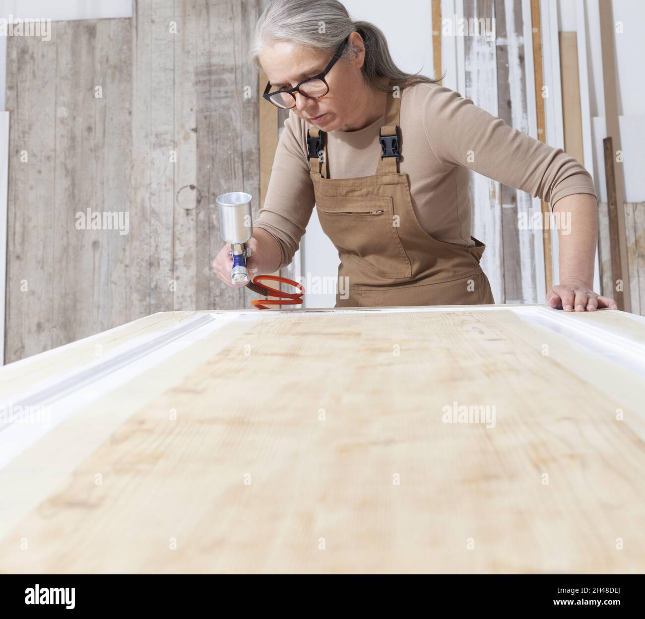 wood crafts, woman artisan carpenter painting with spray gun paint ...