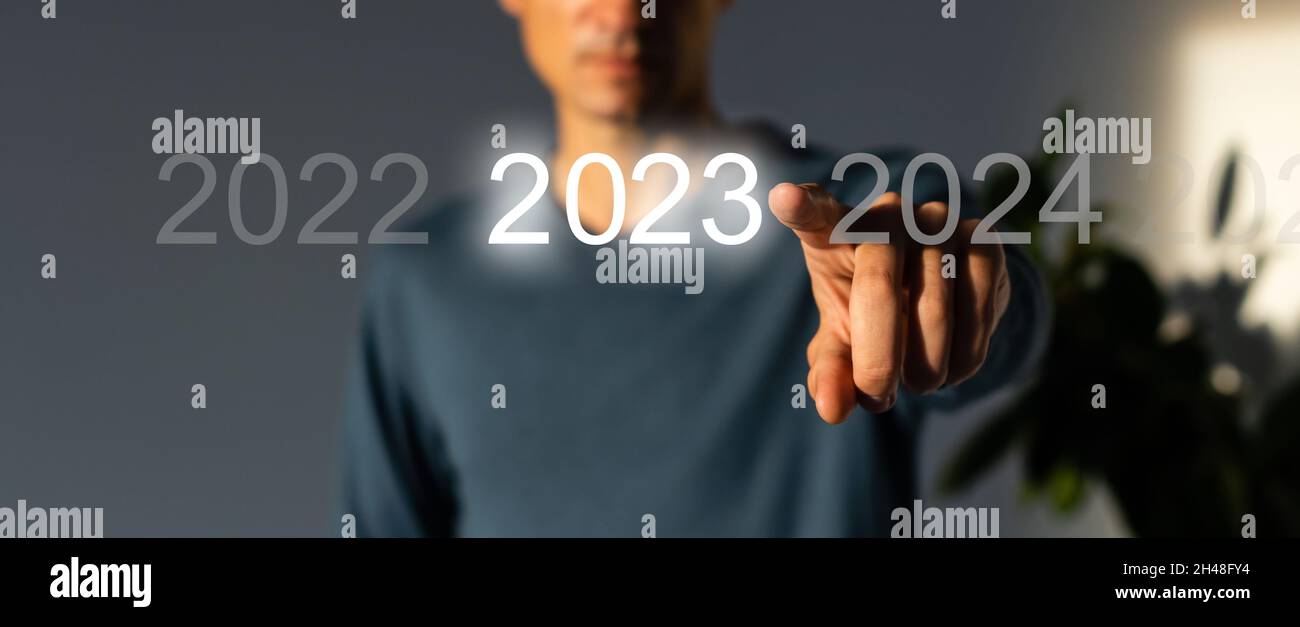 Finger pressing blue start 2023 button on virtual interface on gray ...