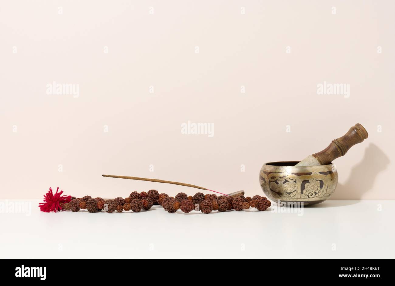 copper singing bowl and wooden clapper on a white table. Musical ...