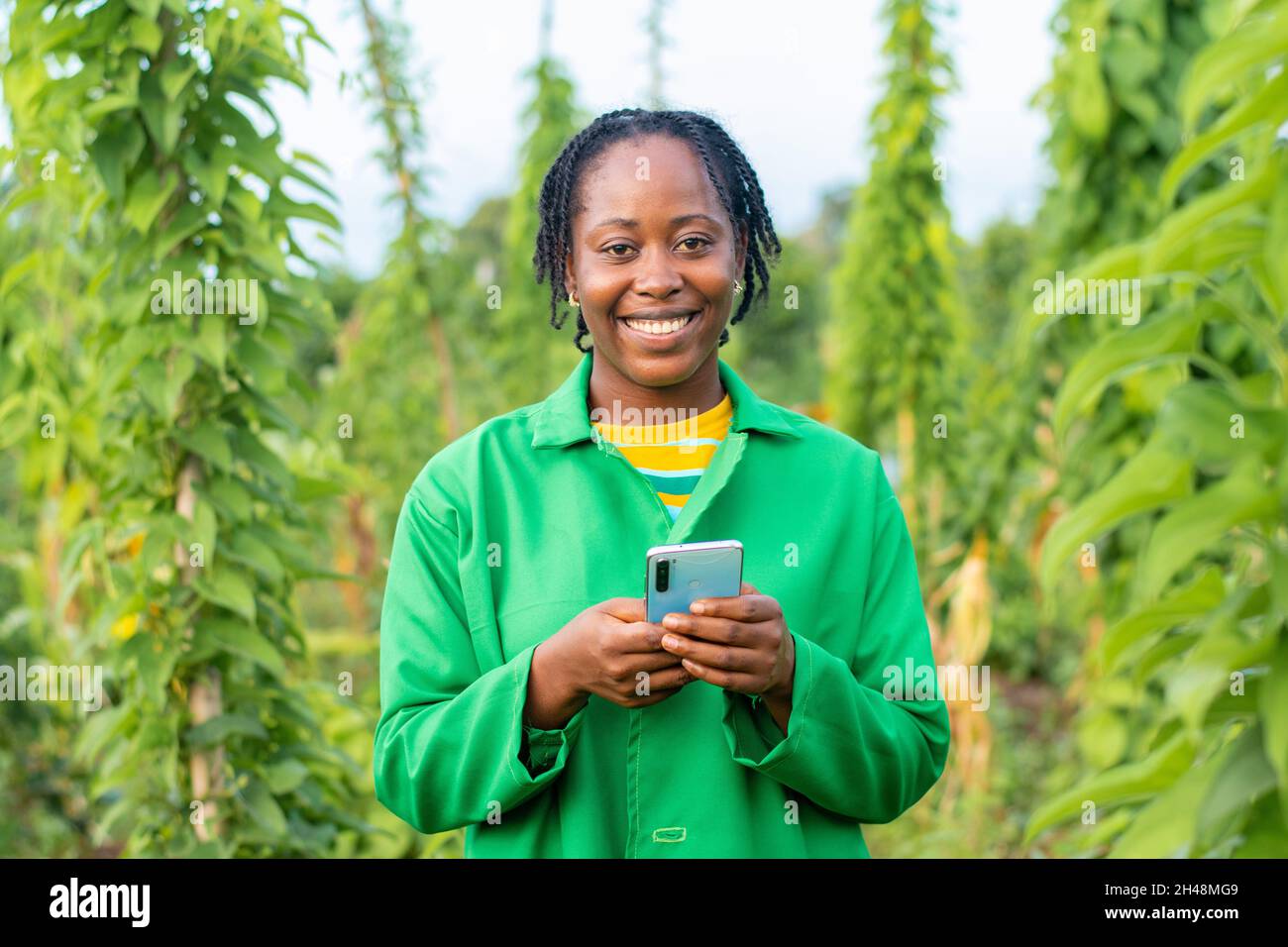 Shot of a happy female African farmer in Nigeria using her smartphone ...
