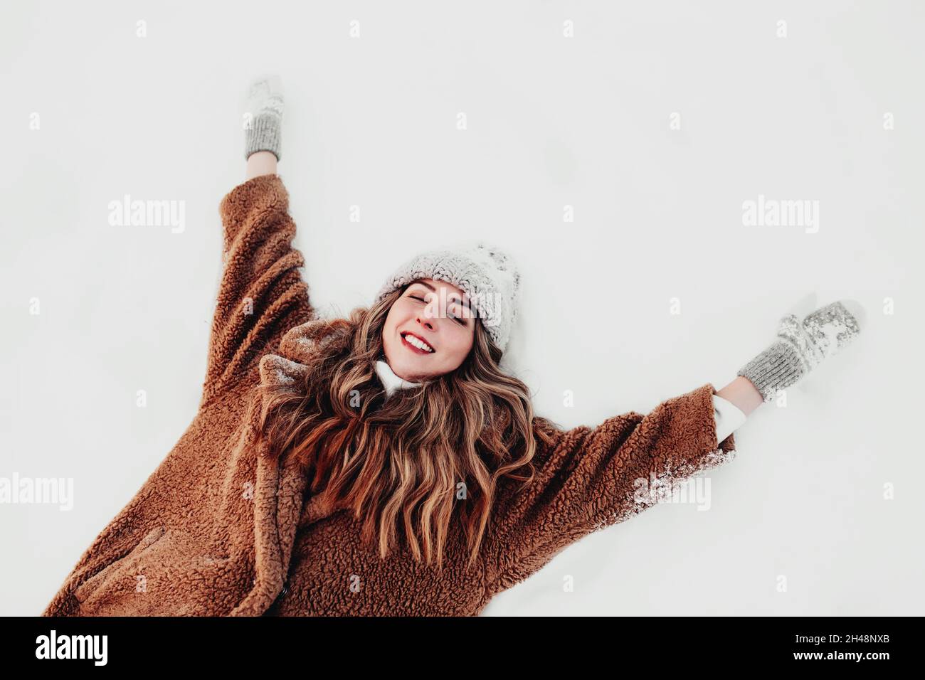 Young beautiful woman laying down on the white snow in the winder ...