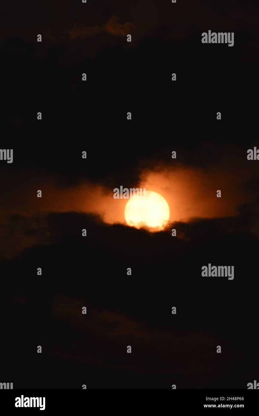 Light orange moon in the sky surrounded by dark clouds Stock Photo - Alamy
