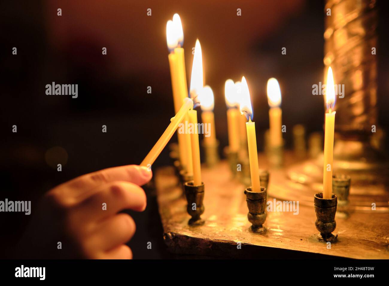 Little Boy lighting a church candle. A Child lights a candle in a ...