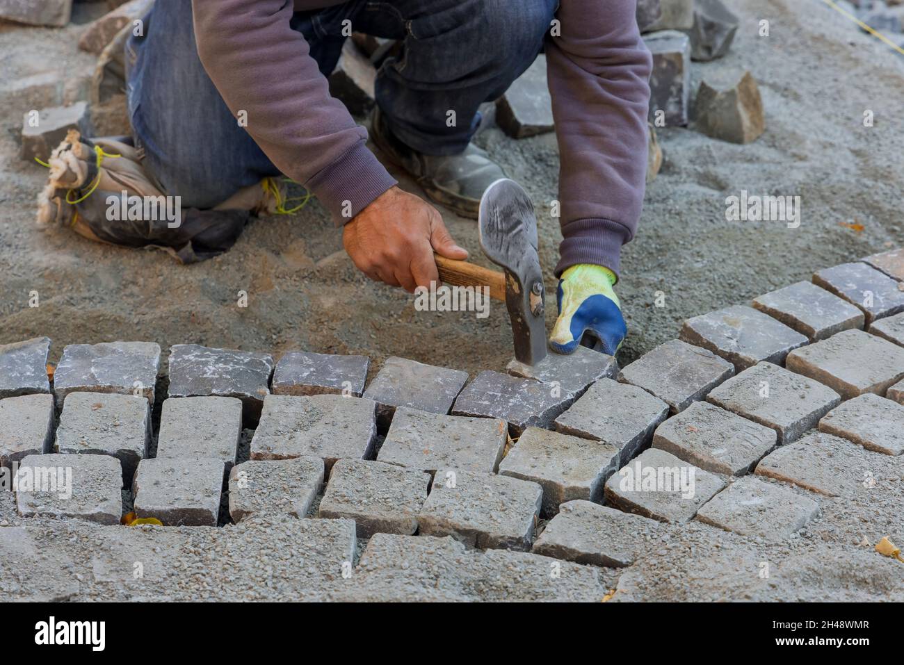 Paving pavement with granite stones, workers using industrial ...