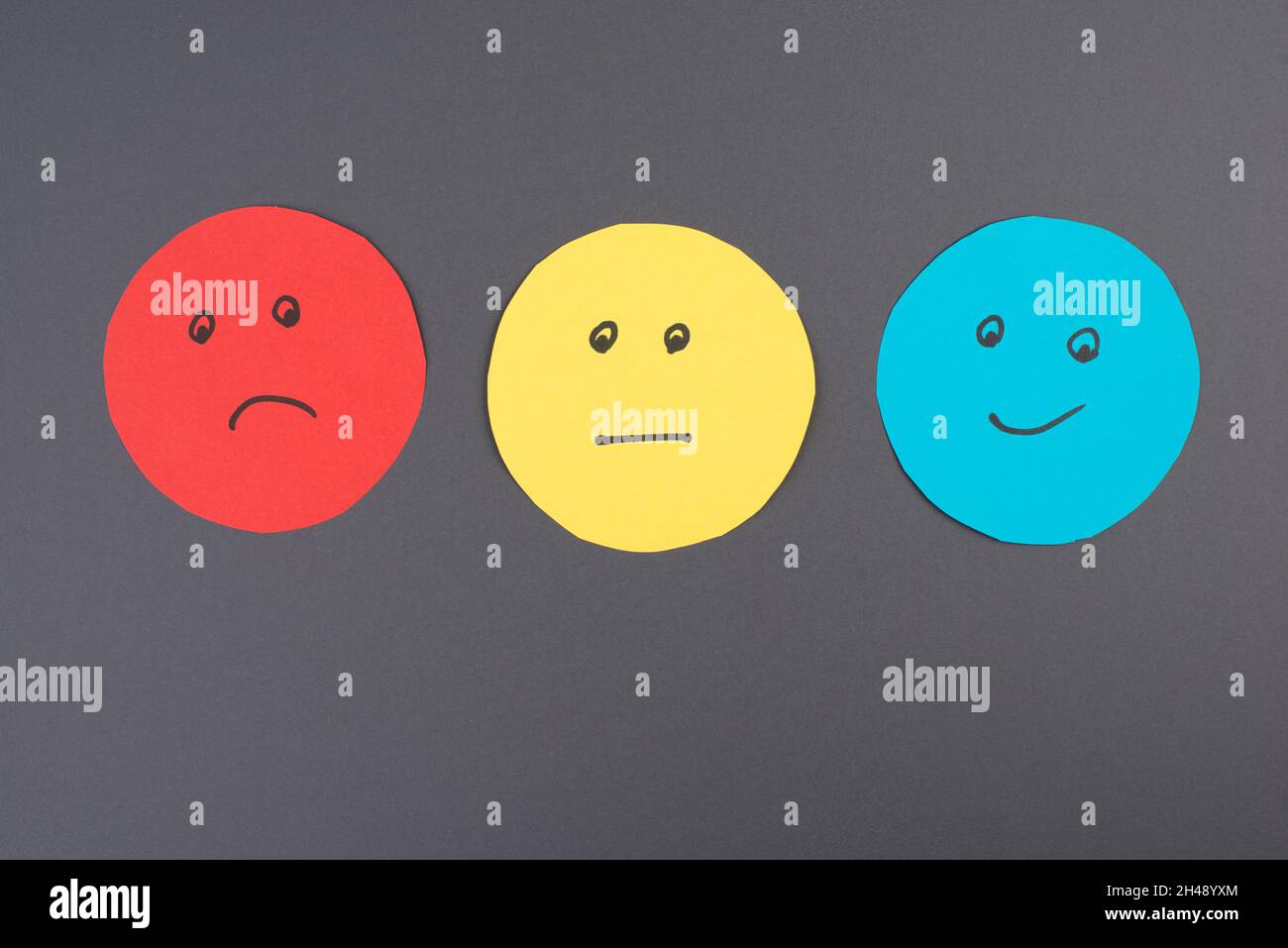 Three faces, smiling, sad in different colors on a unicolor background ...