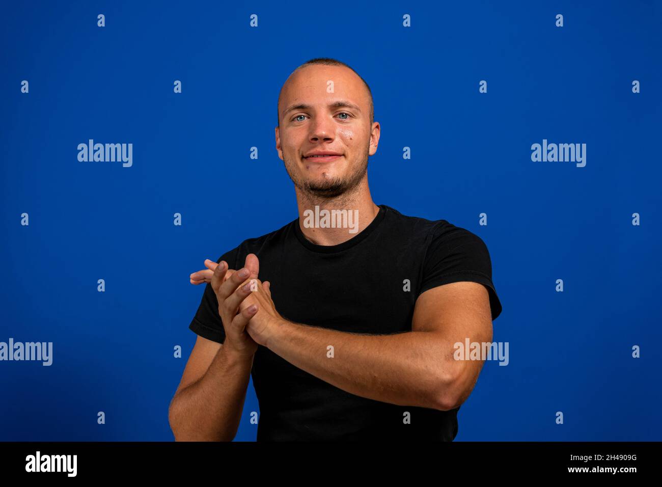 Smiling Young Handsome Man Clapping Hands on blue studio background ...