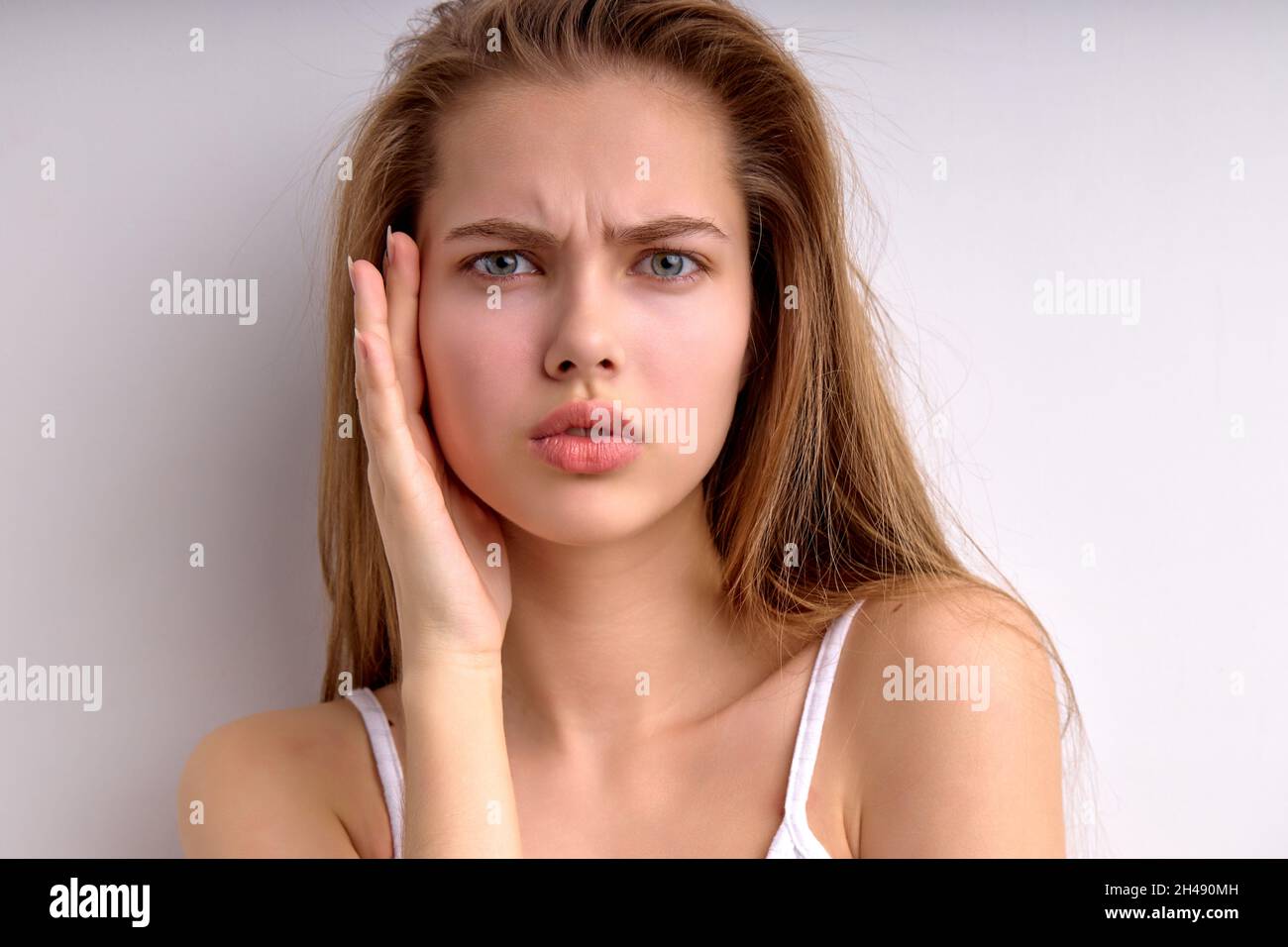 Upset female touching face, having dissatisfied facial expression ...