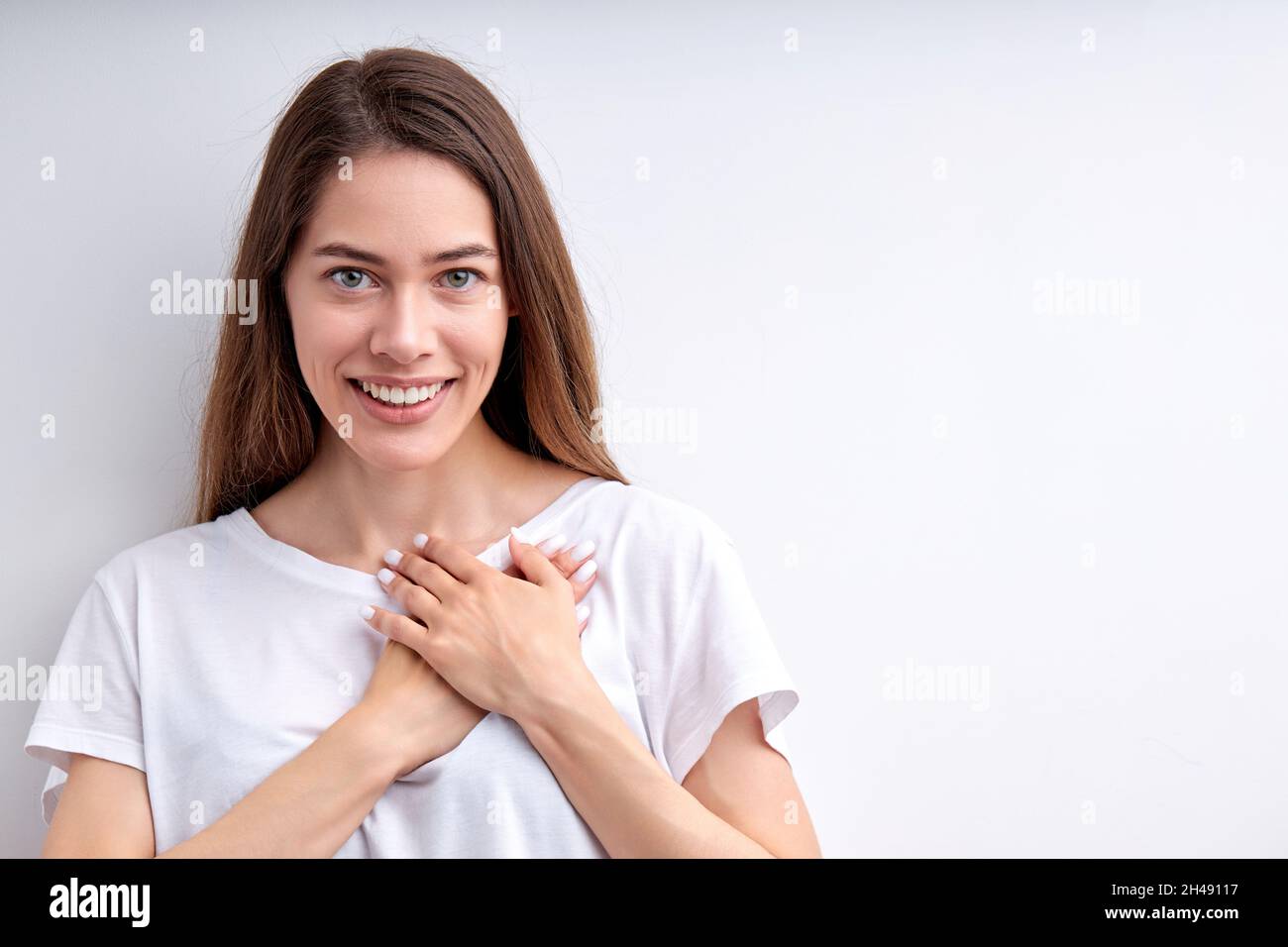 Attractive happy woman expressing gratitude, holding hands on chest ...
