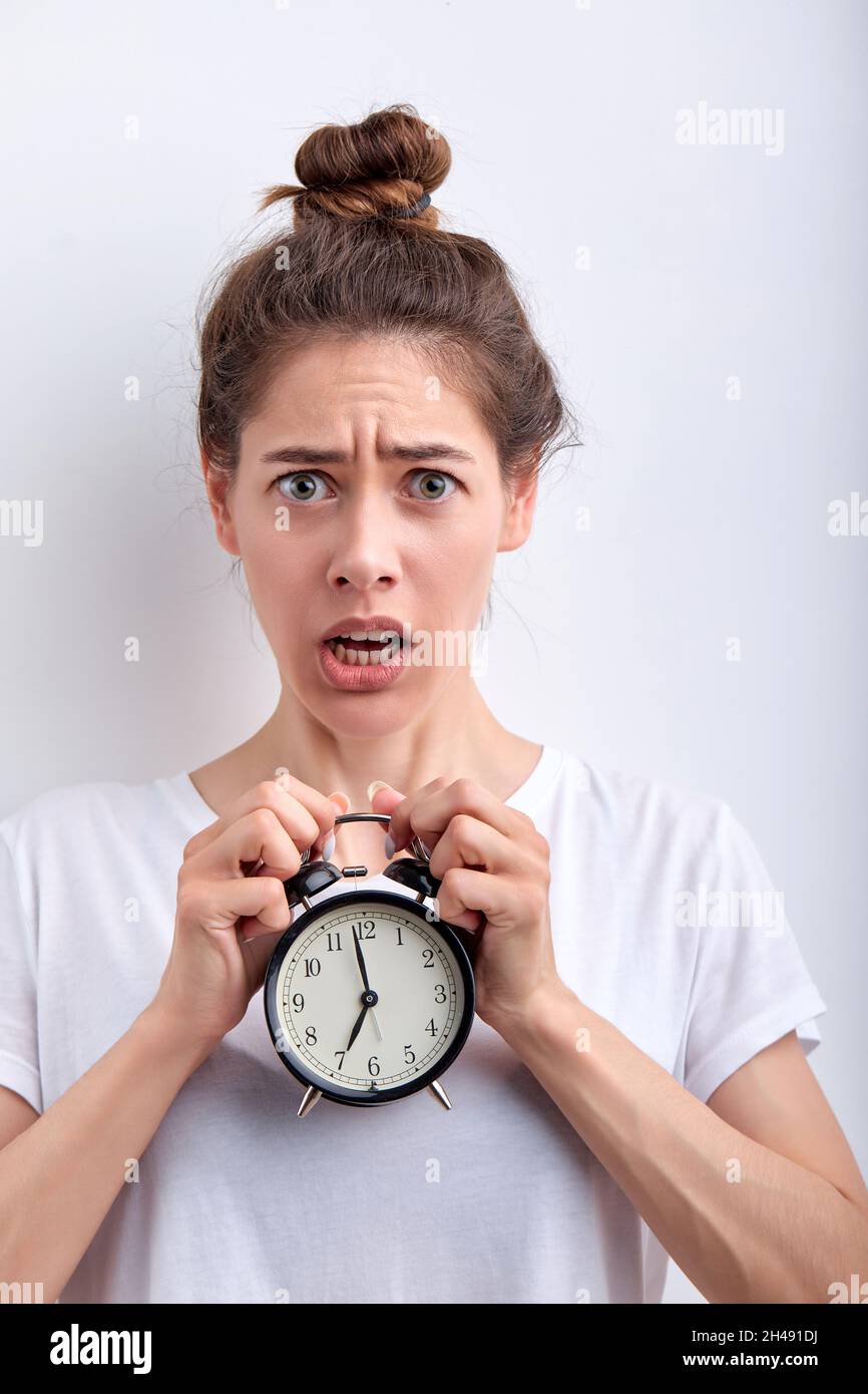 Amazed surprised woman holding alarm clocks in hands in shock, in the ...