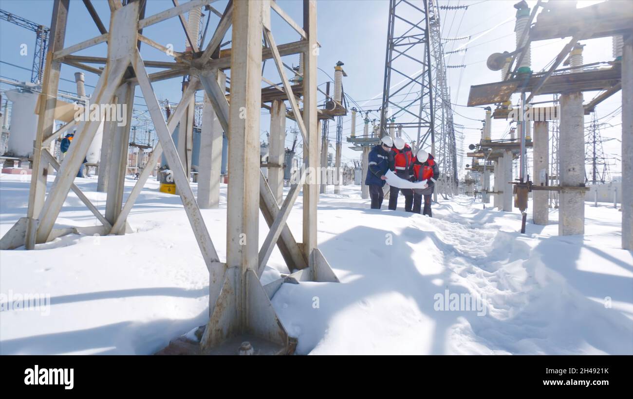 Engineers at electrical substation in winter. Action. Engineers and ...