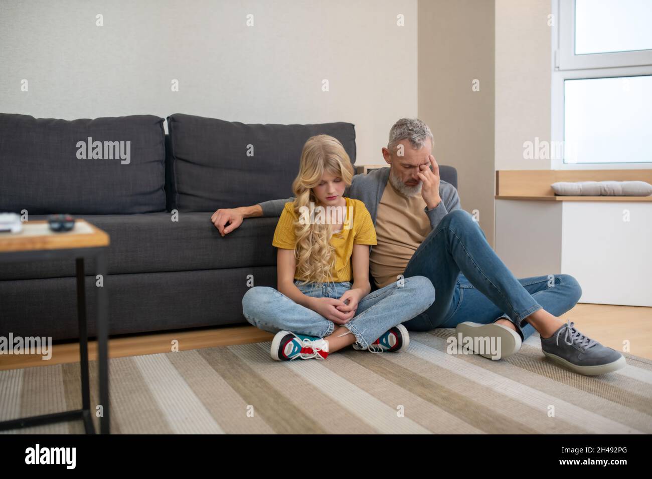 A blonde girl sharing her bad mood with her dad Stock Photo - Alamy